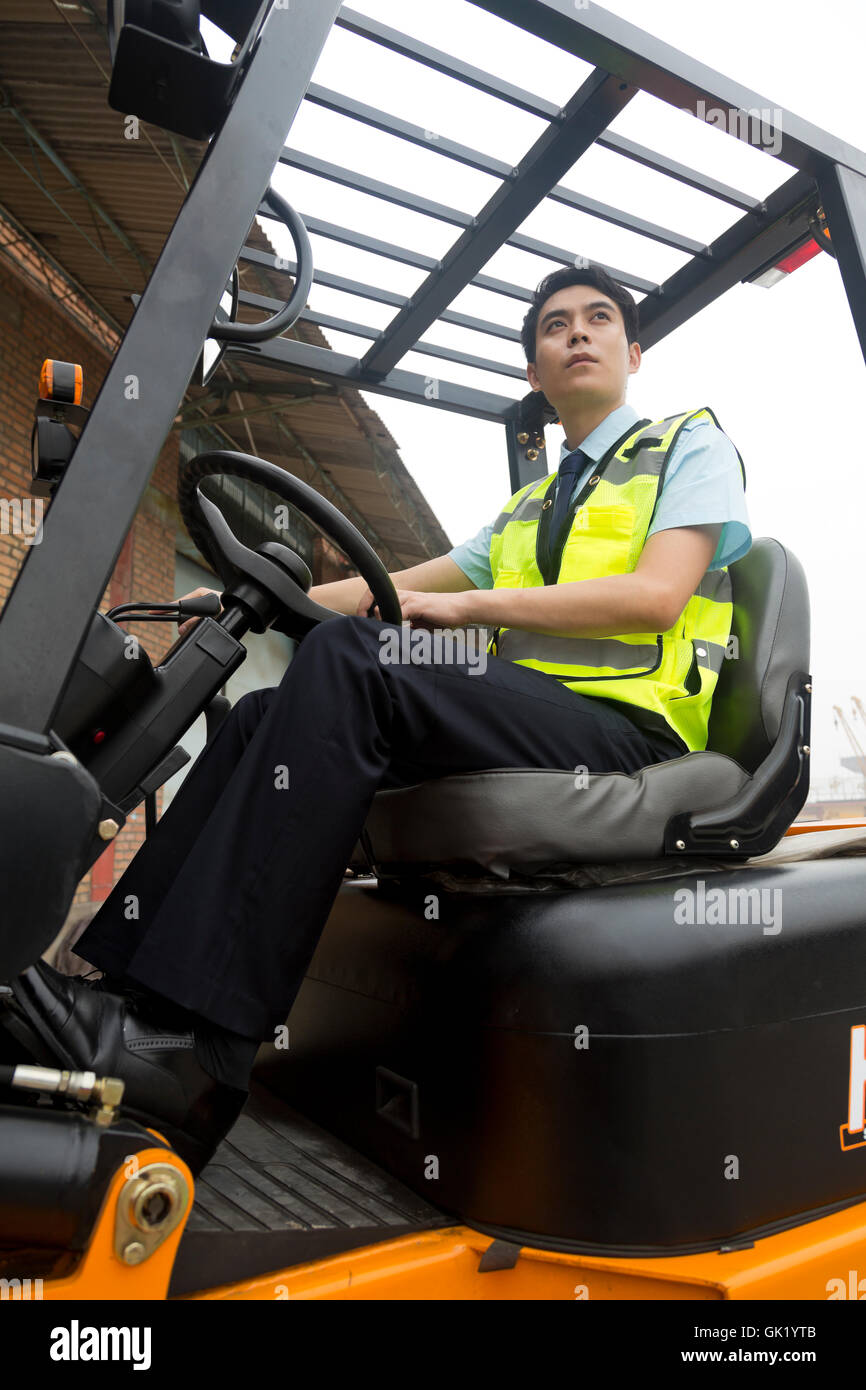 Warehouse worker driving forklift Stock Photo - Alamy