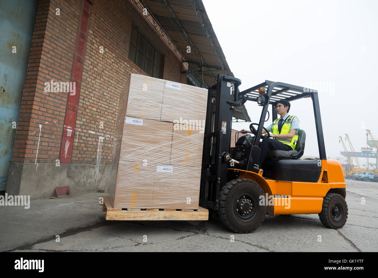 Warehouse worker driving forklift Stock Photo - Alamy