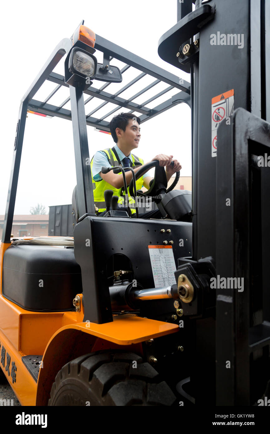 Warehouse worker driving forklift Stock Photo - Alamy