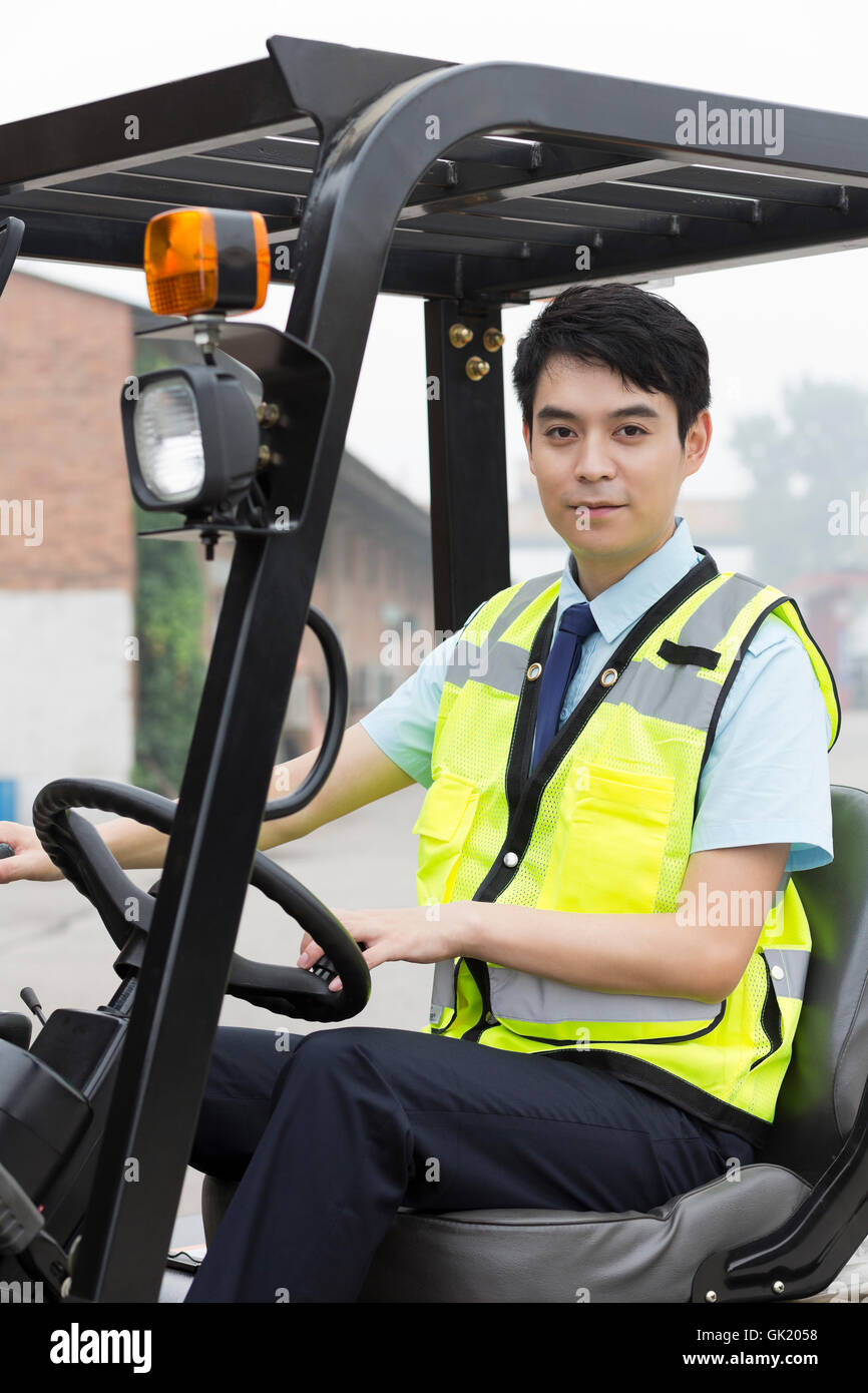 Warehouse worker driving forklift Stock Photo - Alamy