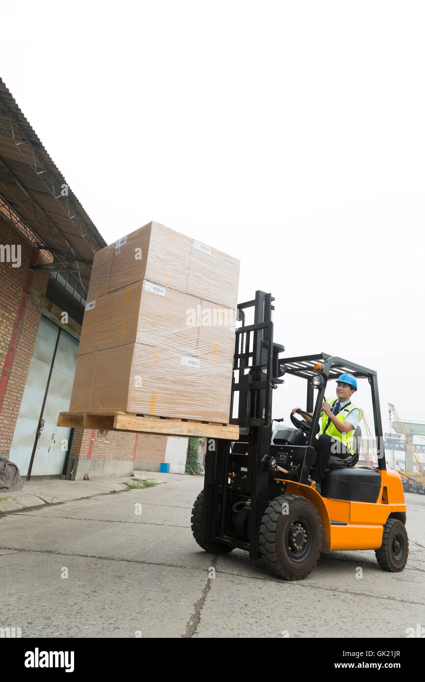 Warehouse worker driving forklift loading and unloading cargo Stock ...