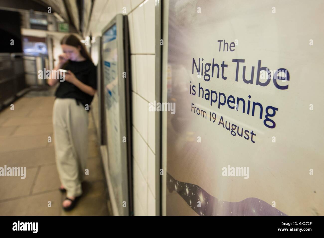 A passenger stands near an advert for the night tube on a platform at ...