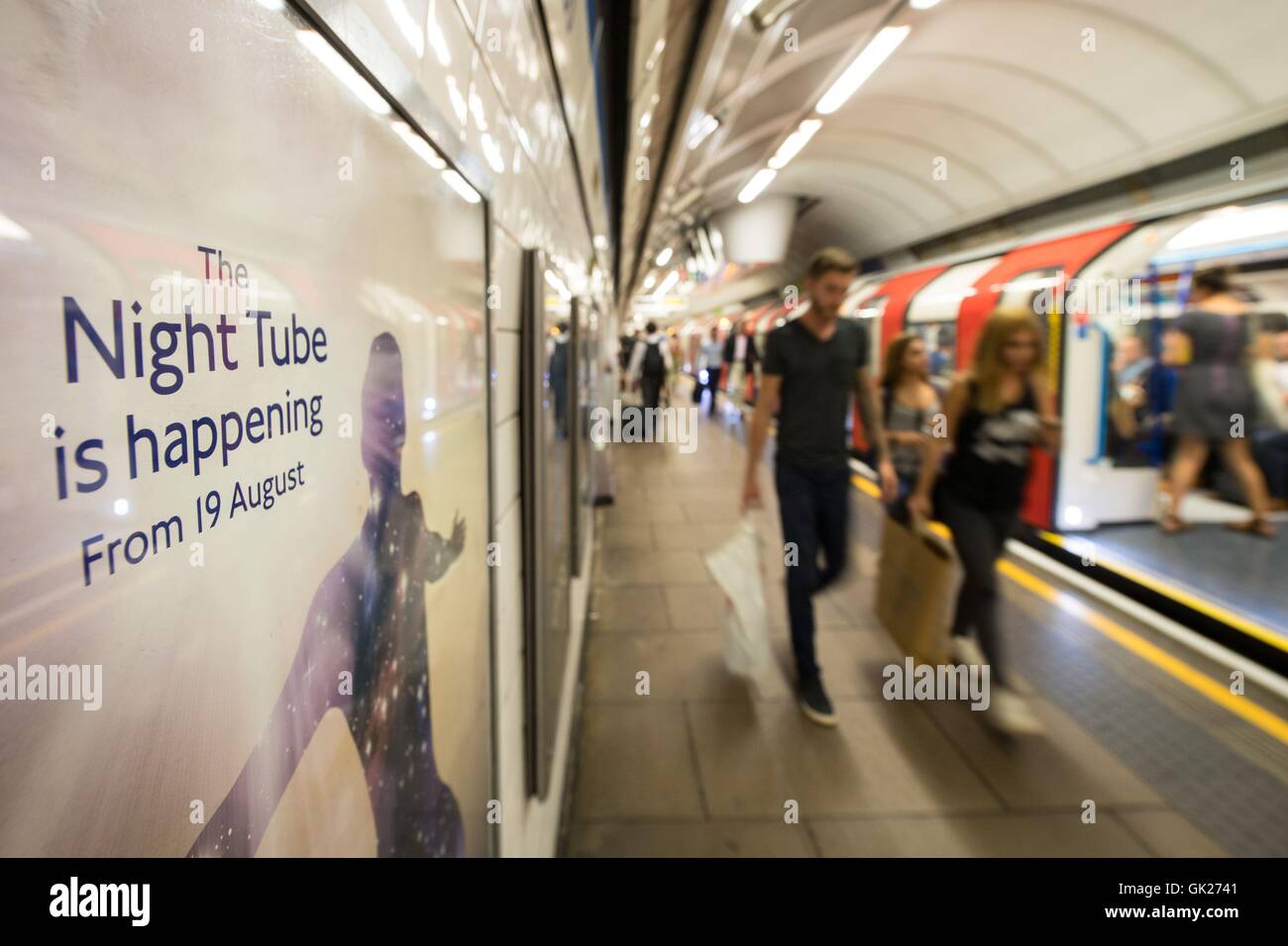 Passengers pass an advert for the night tube on a platform at Oxford ...