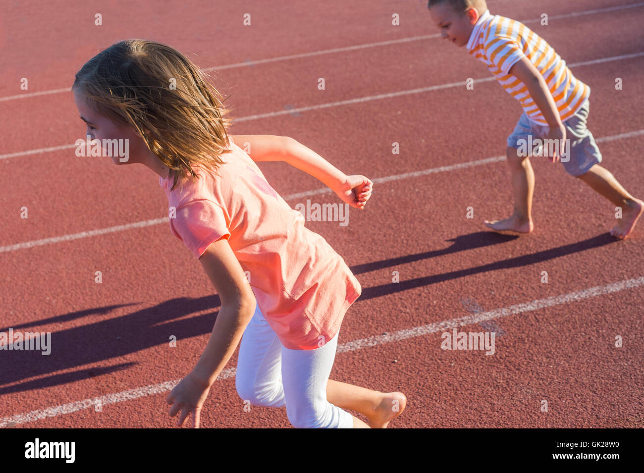 Happy girl and boy run on the track Stock Photo - Alamy