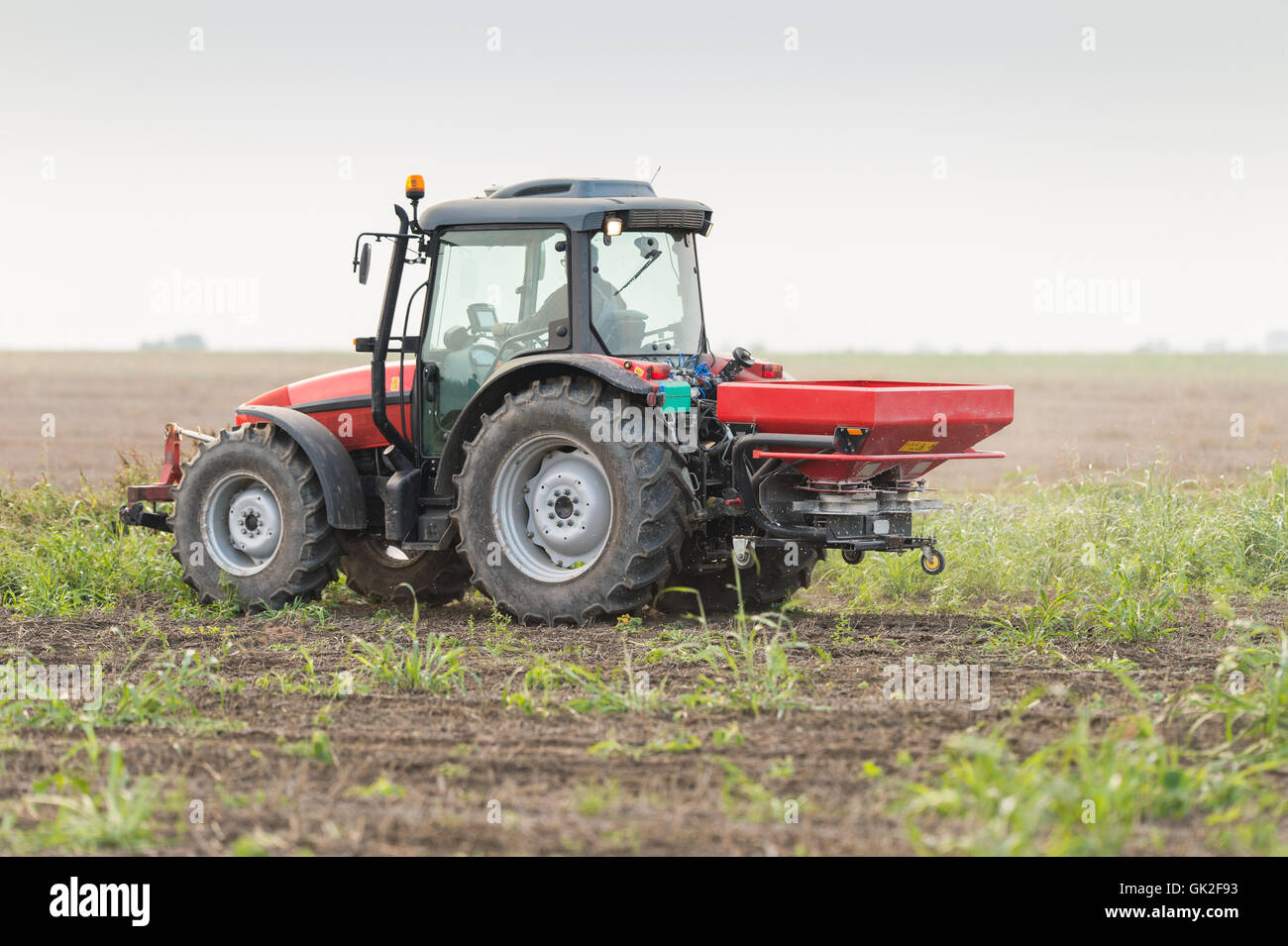 Tractor and fertilizer spreader in field Stock Photo - Alamy