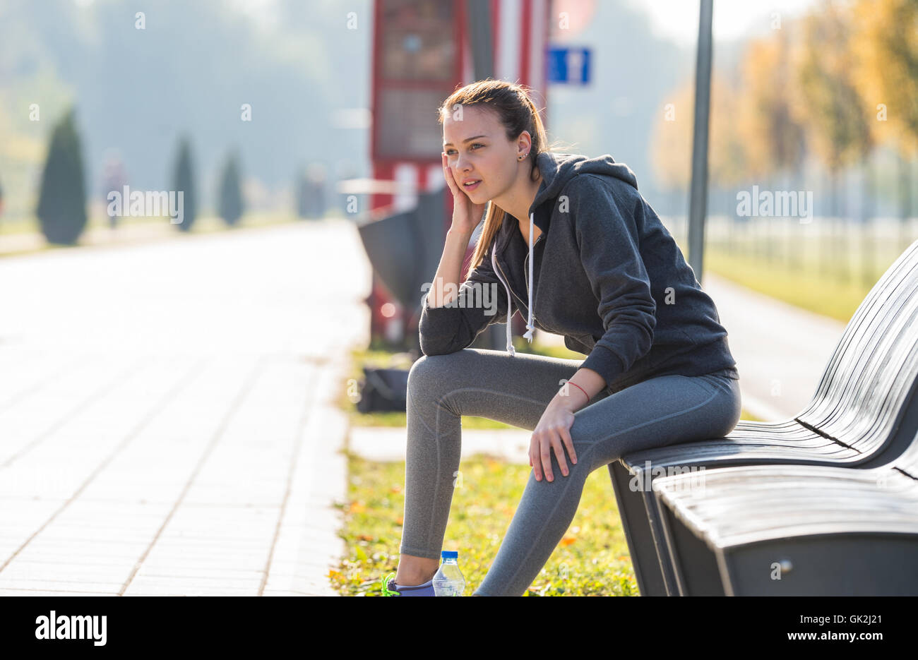 Girl sitting on a park bench after running Stock Photo - Alamy
