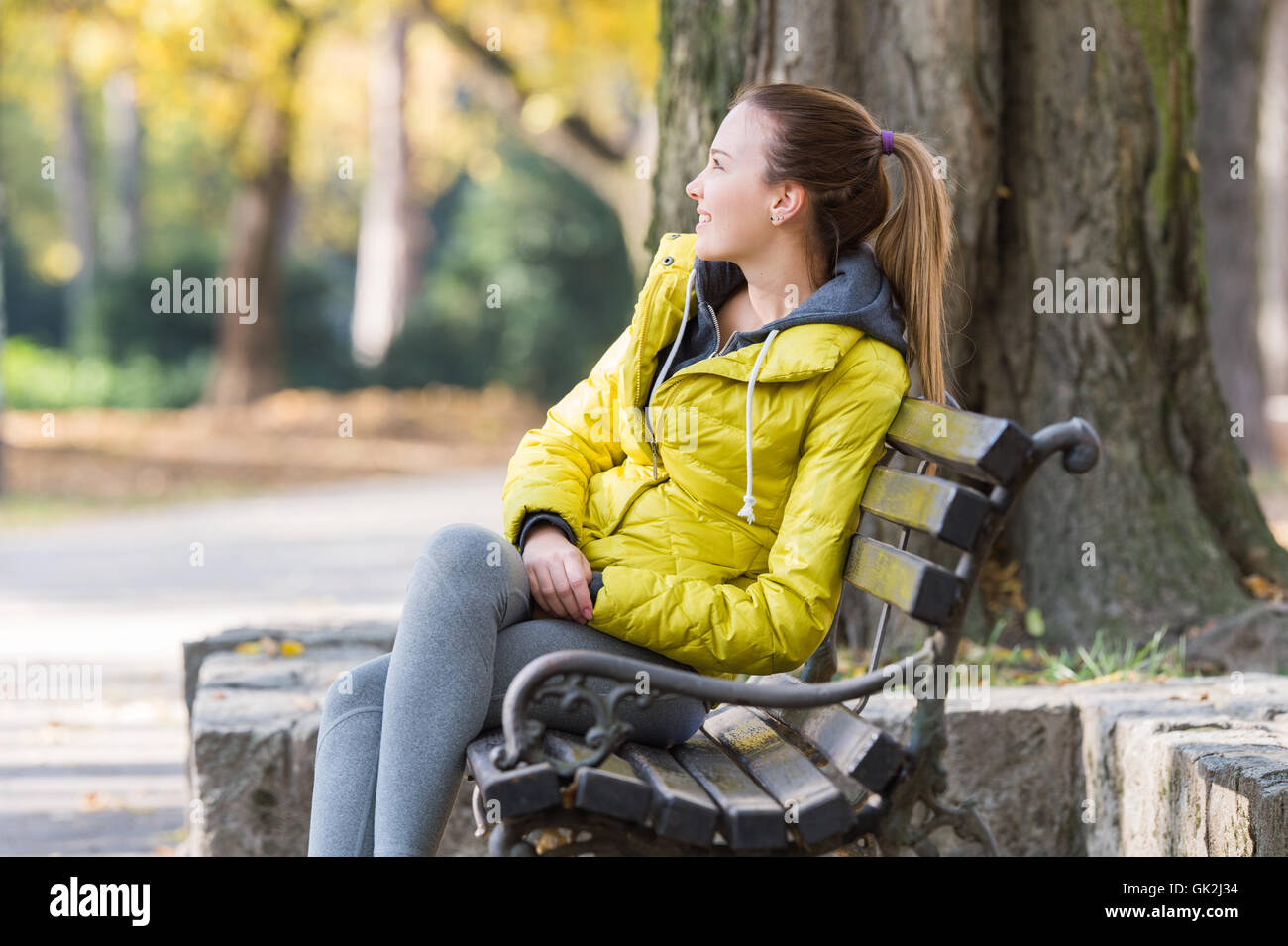 Girl sitting on a park bench after running Stock Photo - Alamy