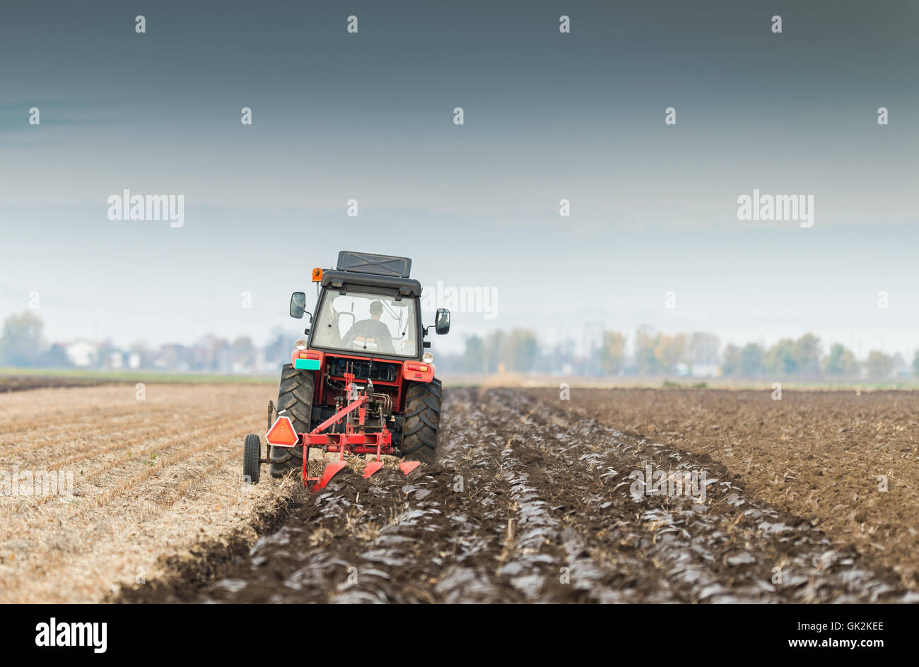 Tractor plowing field at sunset Stock Photo - Alamy