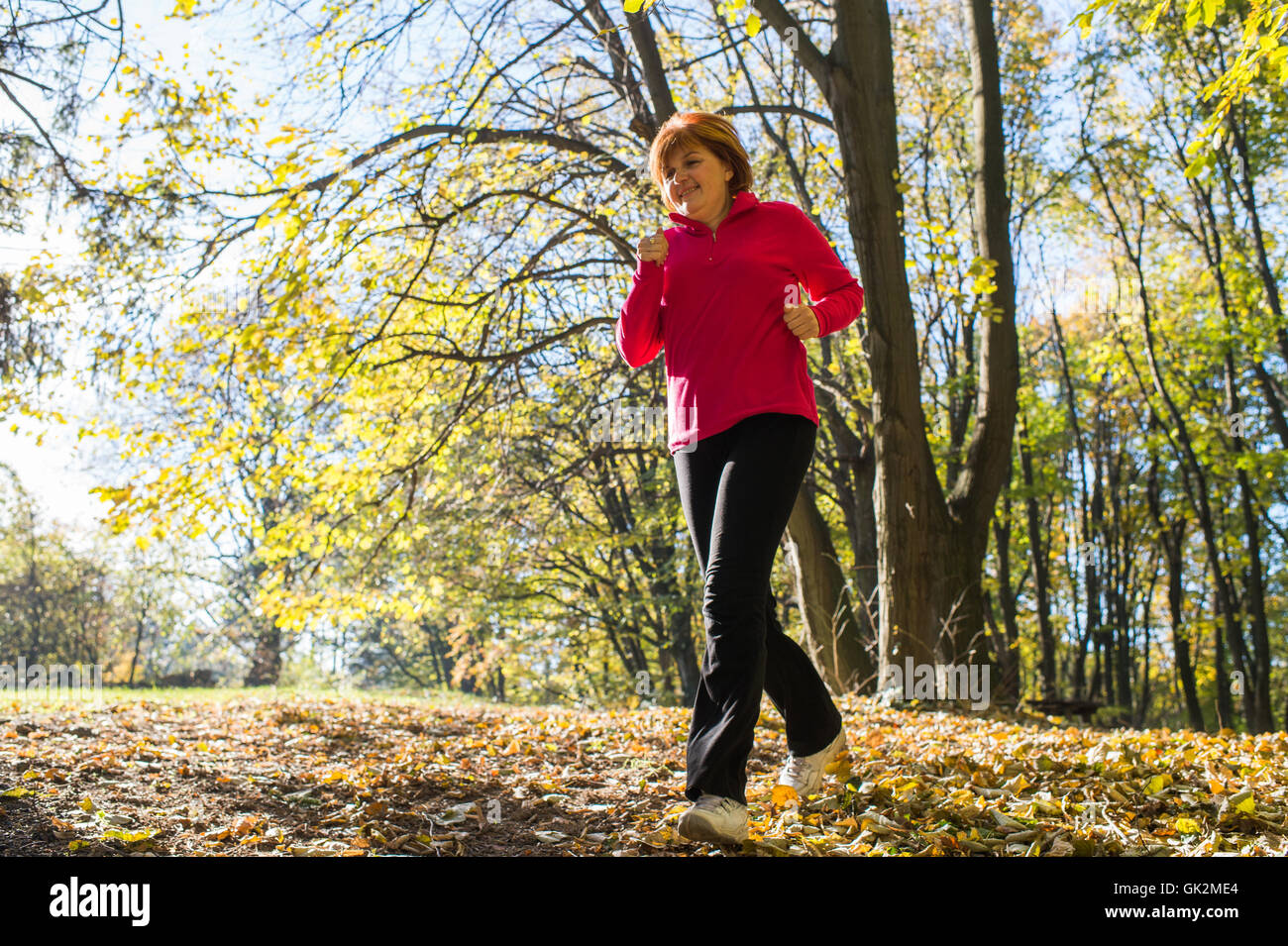 Woman running in autumn park Stock Photo - Alamy