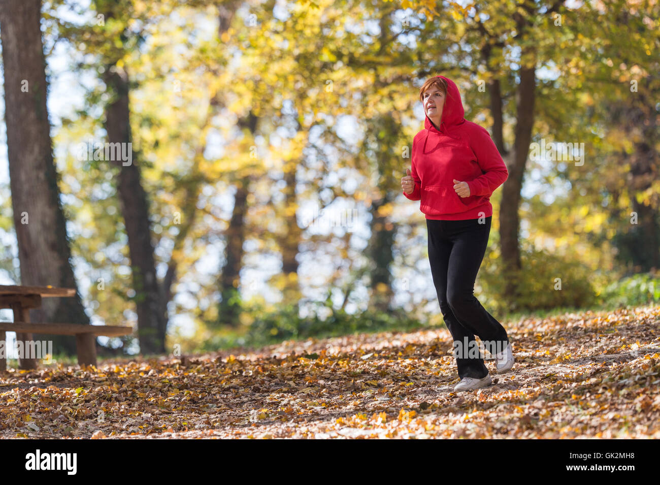 Woman running in autumn park Stock Photo - Alamy