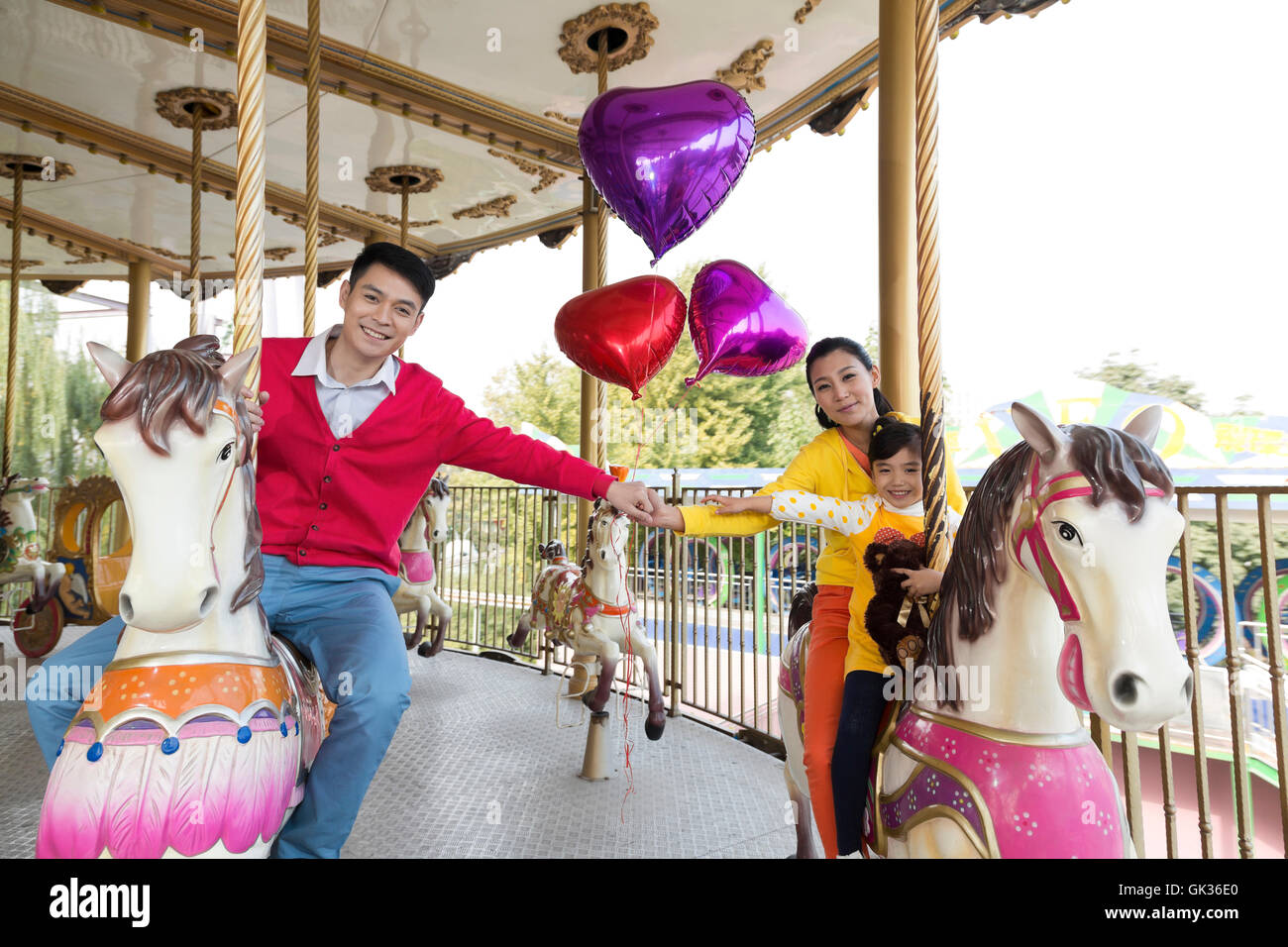 Happy family of three to go to the amusement park ride carousel Stock ...