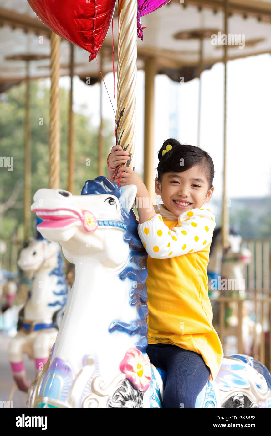 The little girl in the amusement park ride carousel Stock Photo - Alamy