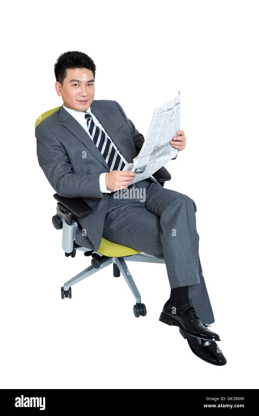 Studio shot business man reading the newspaper sitting on office chair ...