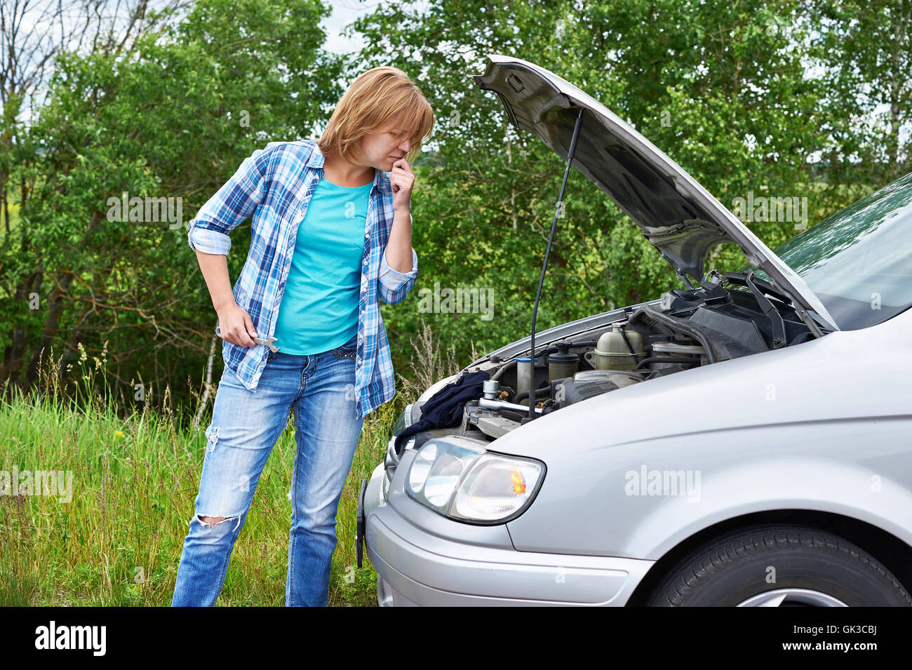 Woman with wrench near her broken car Stock Photo - Alamy