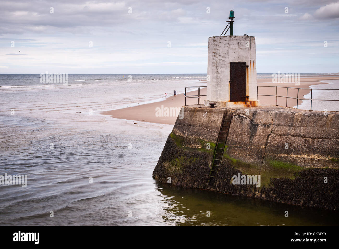 A small stone pier with marker light at the entrance to Nairn harbour ...