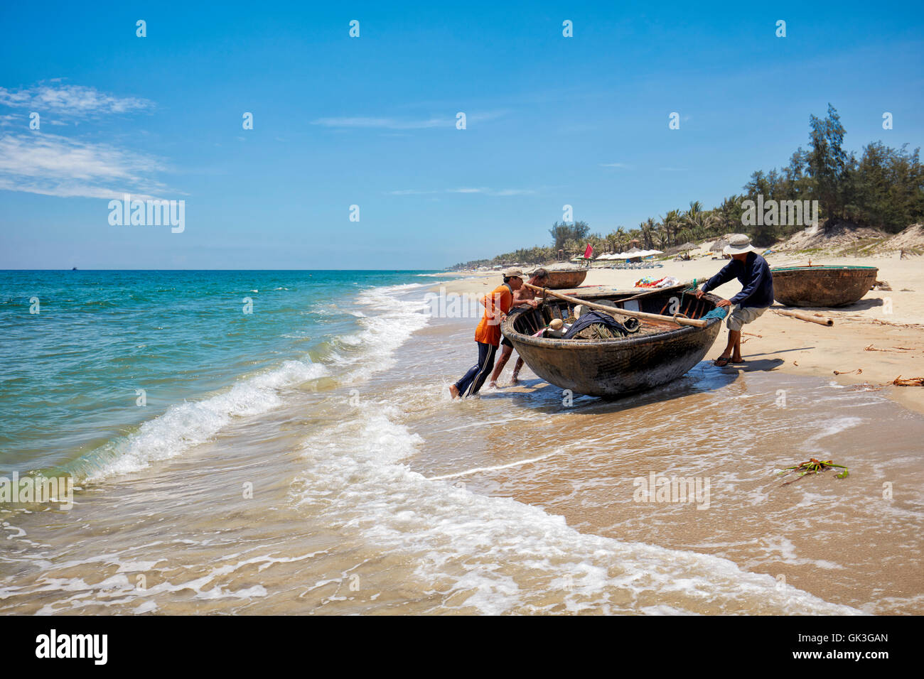 Vietnamese fishermen pull coracle on Cua Dai beach. Hoi An, Quang Nam ...
