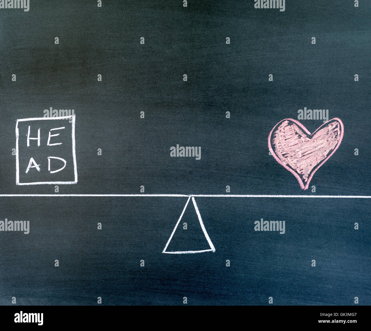 head and heart symbols drawn on a chalkboard, balance scale in ...