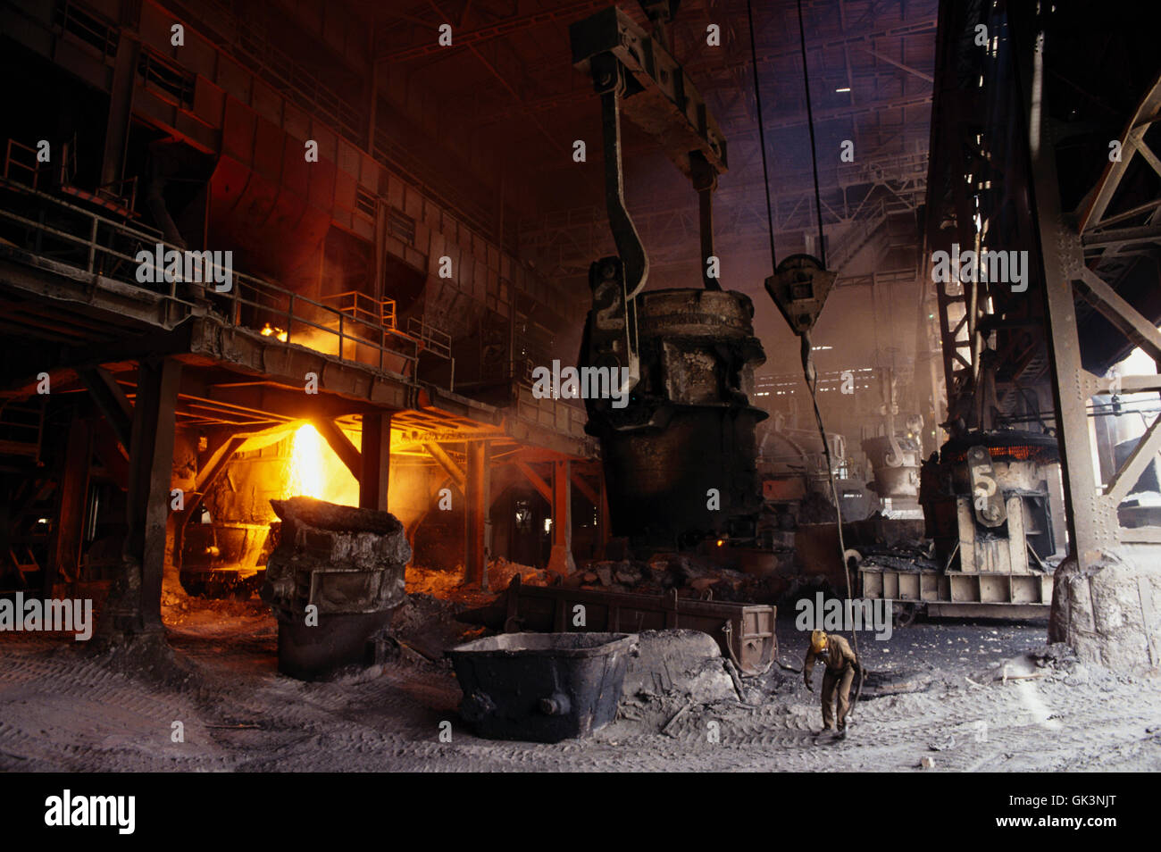 ca. 2003, Boyaca, Colombia --- A worker stands near a molten metal ...