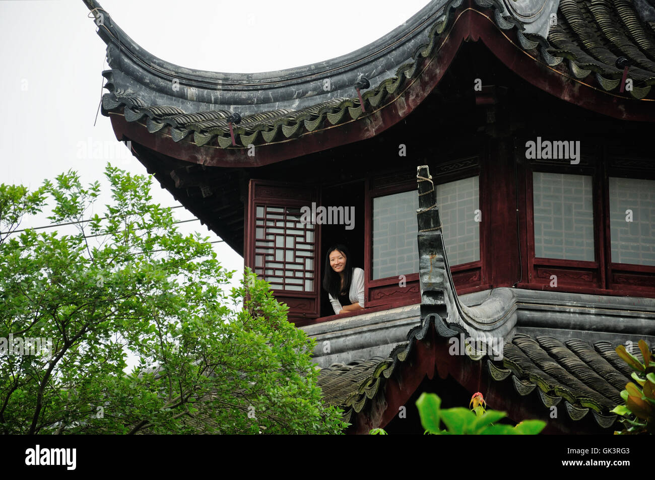 A smiling chinese woman leaning out of a window within a chinese ...