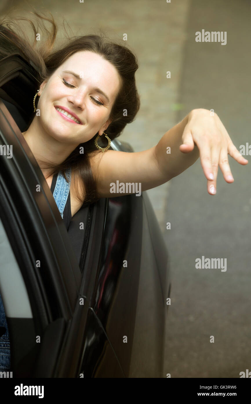 young woman leaning out of car and enjoying the sun and wind Stock ...