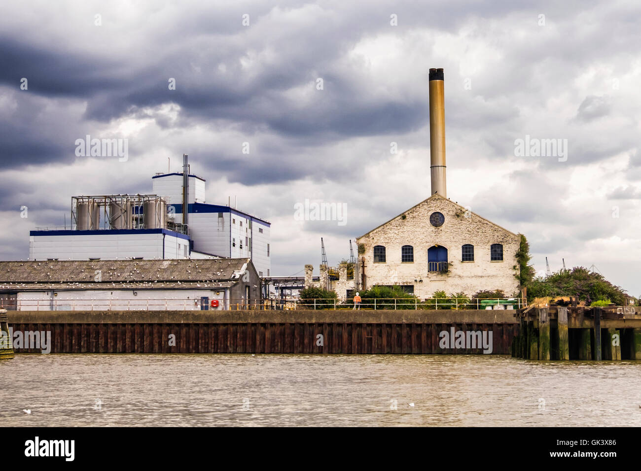 Old riverside warehouse and new factory building on Thames river ...