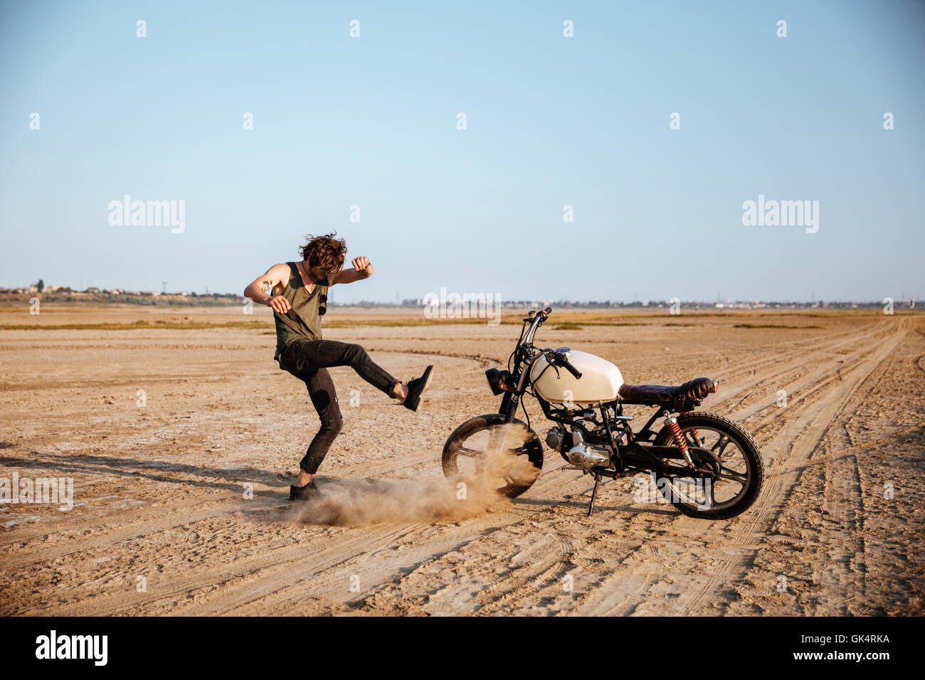 Man making dust standing near his motorcycle at the desert Stock Photo ...