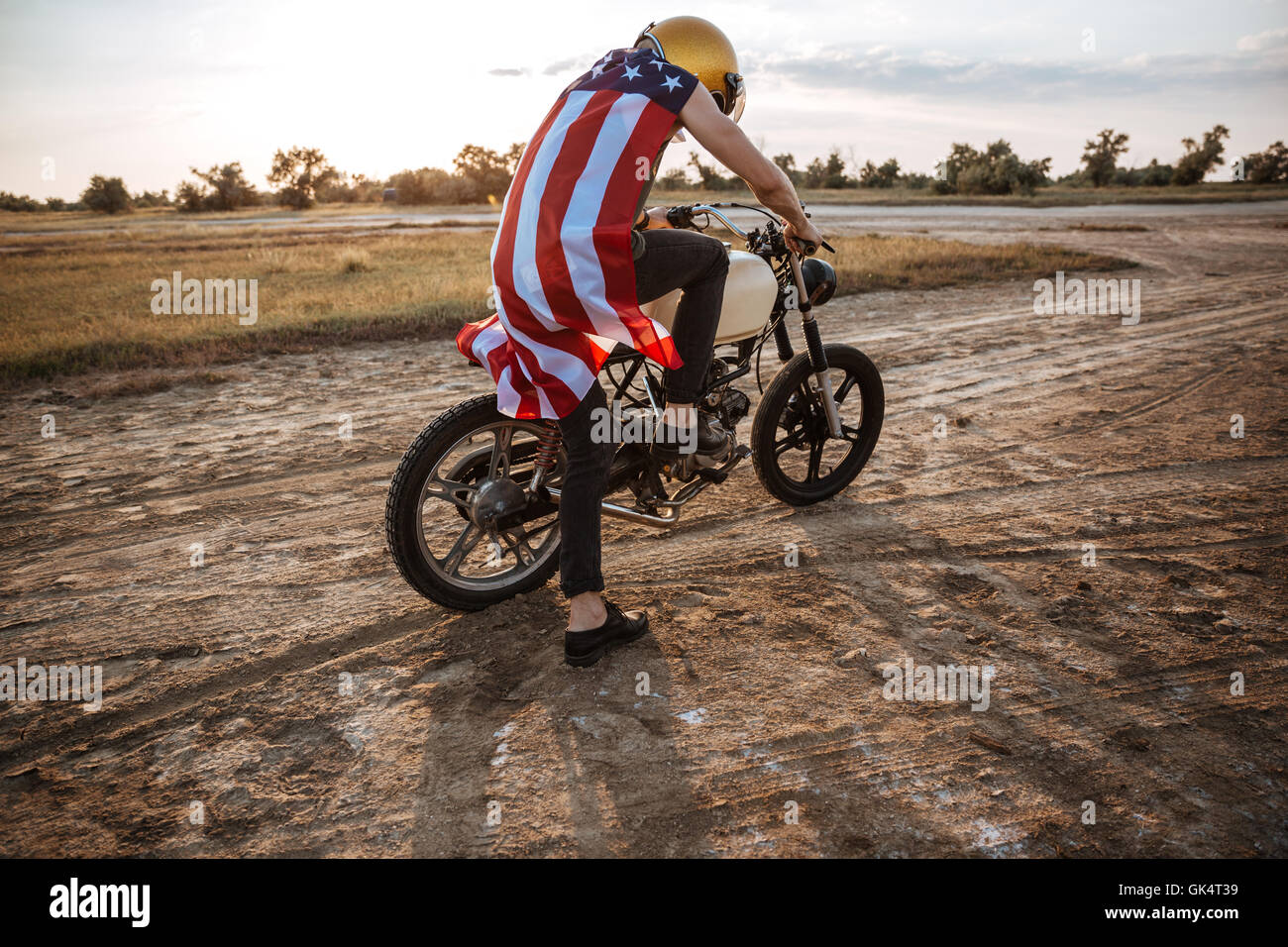 Man in golden helmet and american flag cape starts his motorcycle Stock ...