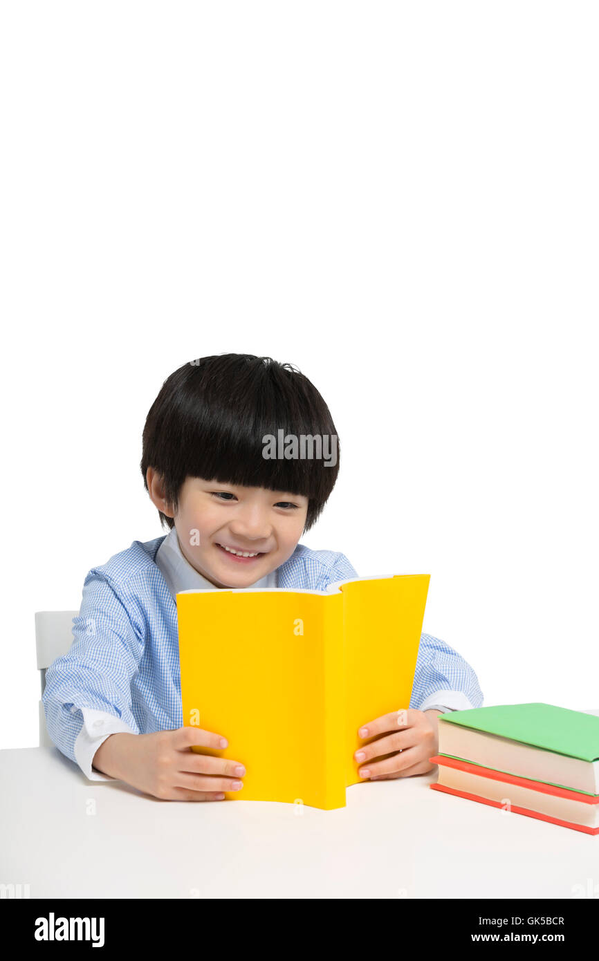 The little boy at the desk reading a book Stock Photo - Alamy