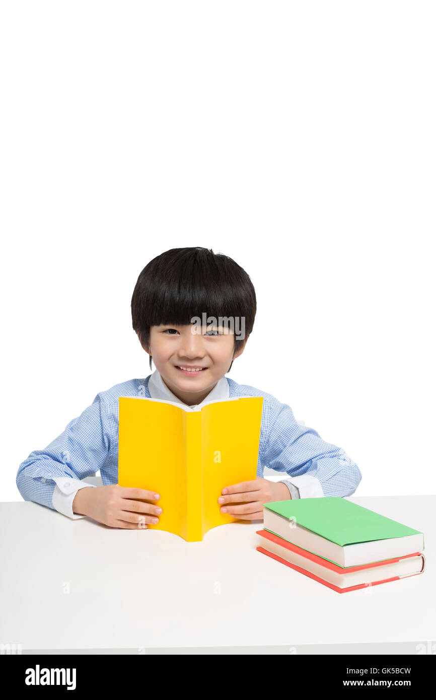 The little boy at the desk reading a book Stock Photo - Alamy