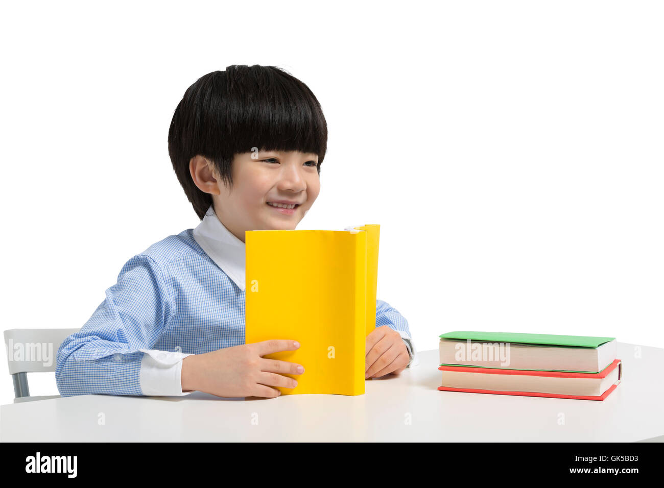 The little boy at the desk reading a book Stock Photo - Alamy