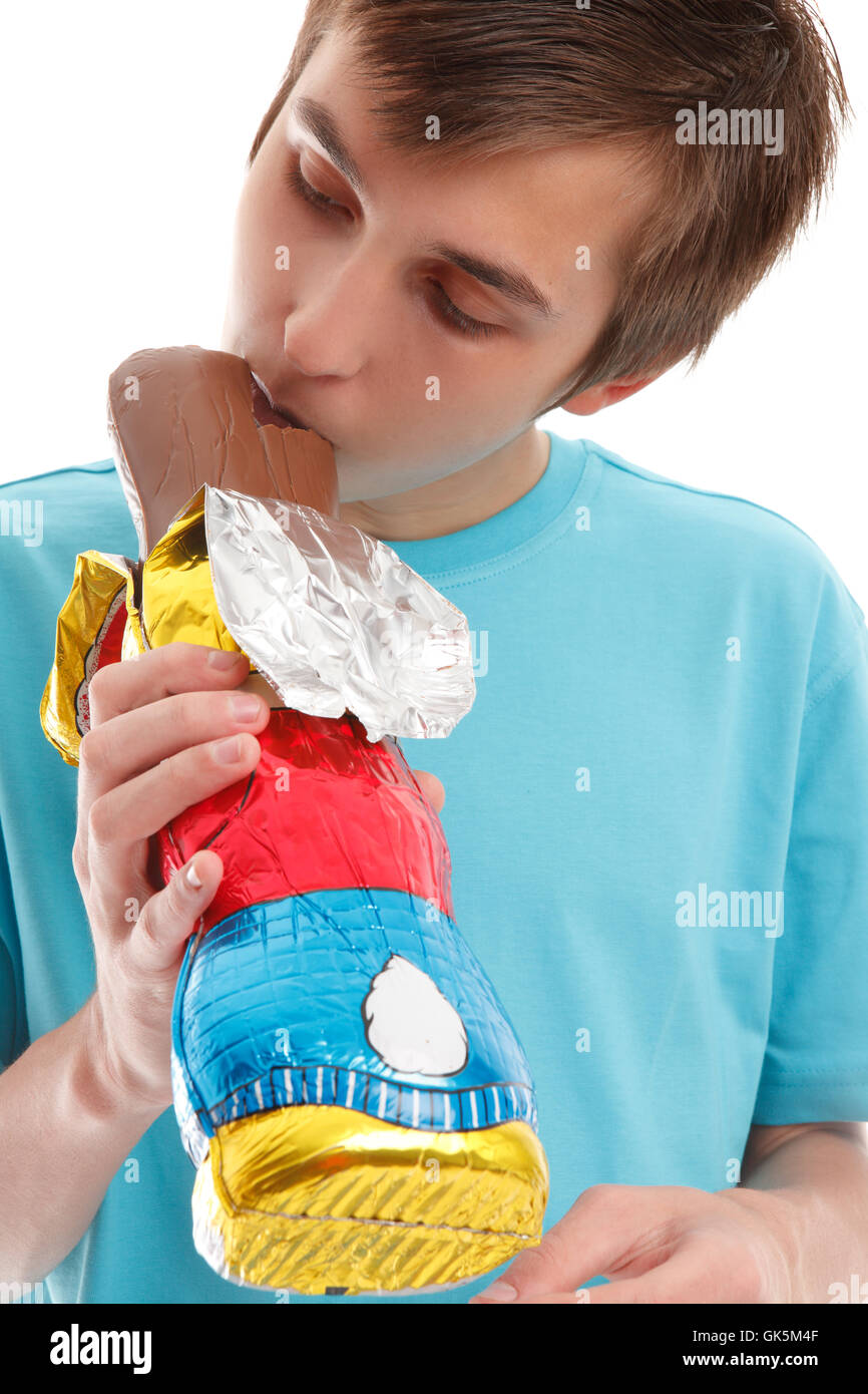 Boy biting ear of chocolate rabbit Stock Photo - Alamy