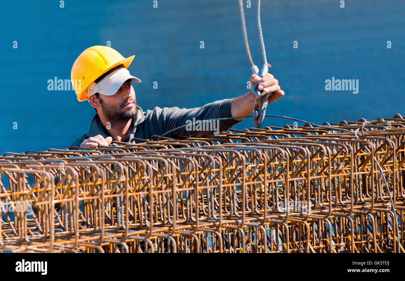 Construction worker loading stack of reinforcement beam cages to Stock ...