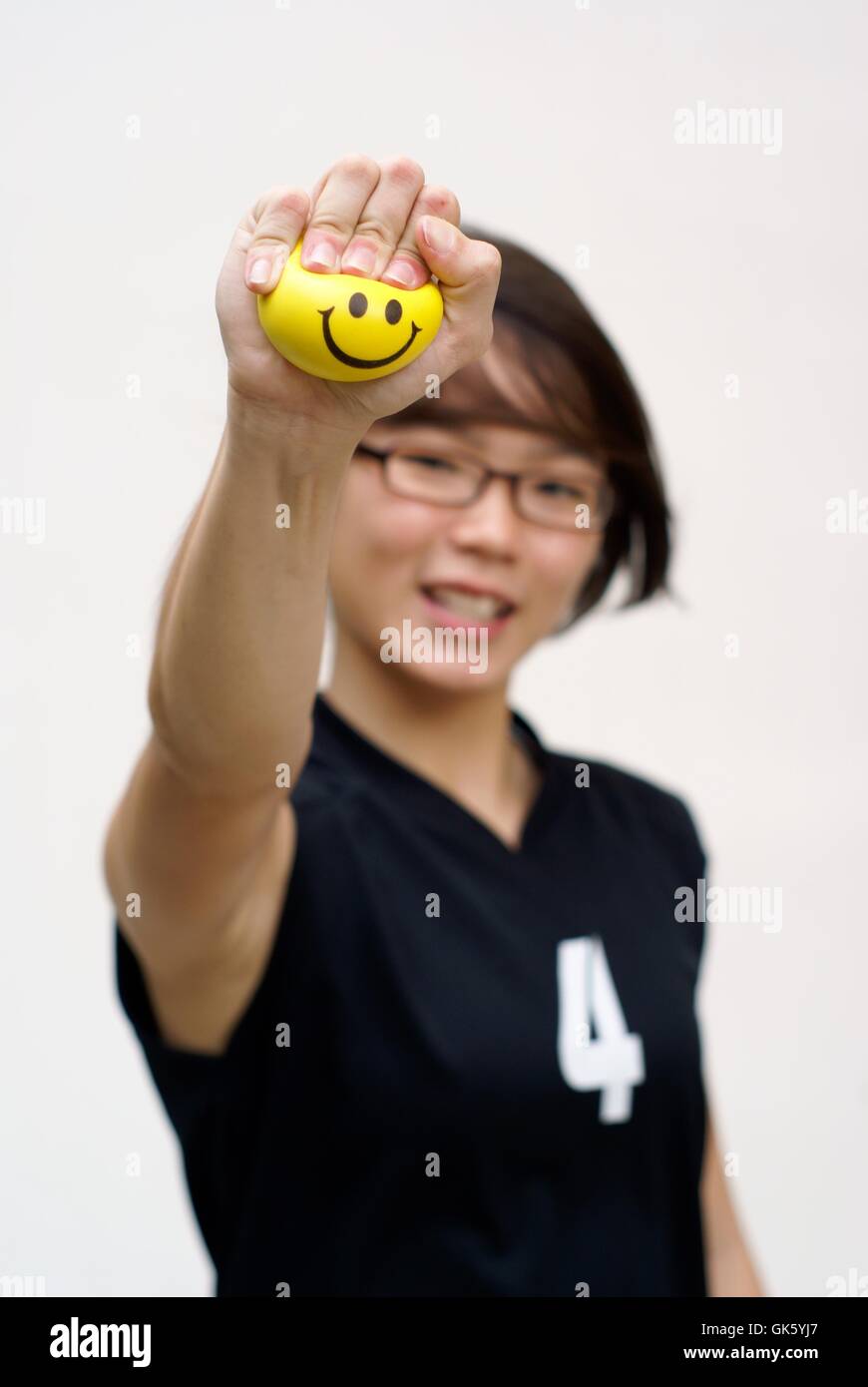 Asian female teen squeezing yellow happy ball Stock Photo - Alamy