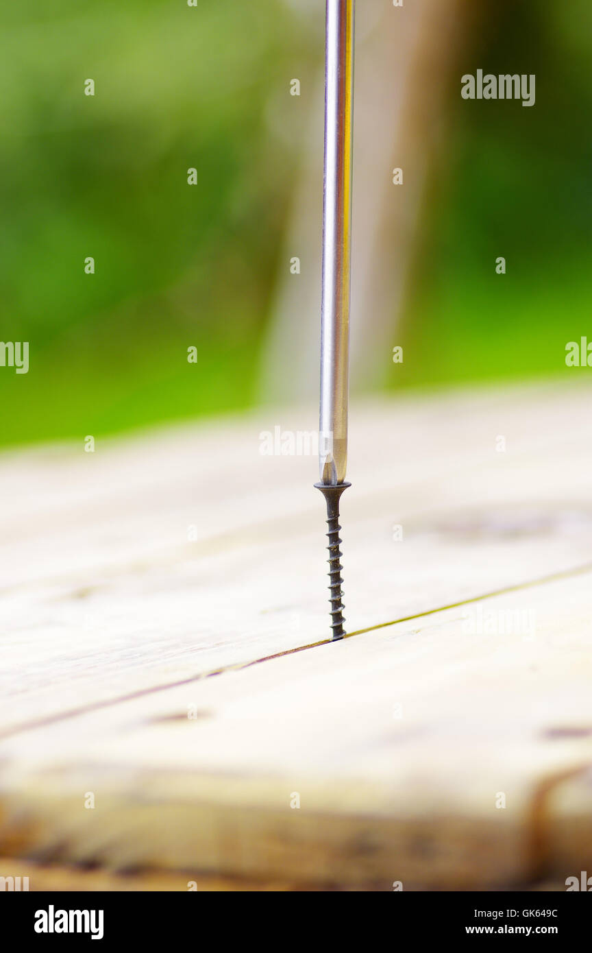 silver screw driver over a black screw on a table Stock Photo - Alamy