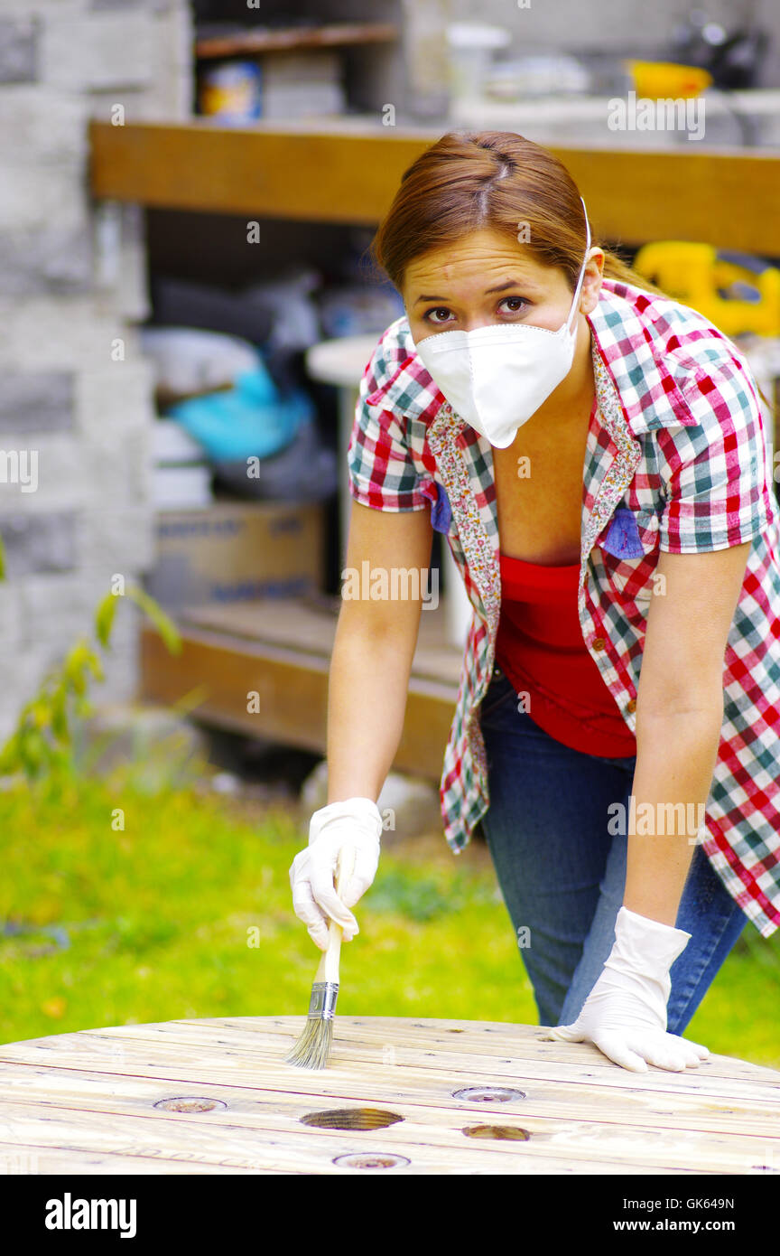 young woman wearing mask and gloves painting a wood table Stock Photo ...