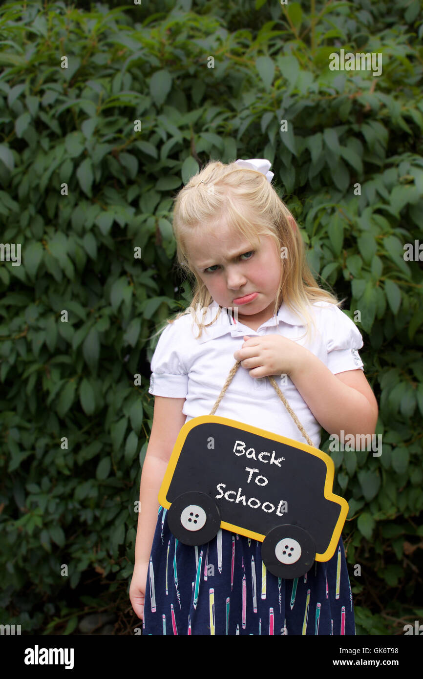 adorable school age girl frowning holding sign back to school Stock ...