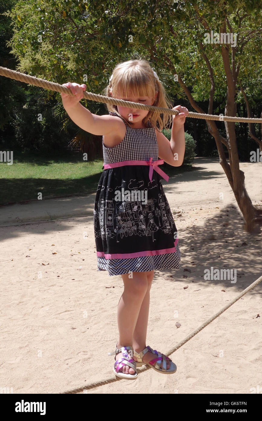adorable school age girl balancing on ropes at park playground Stock ...