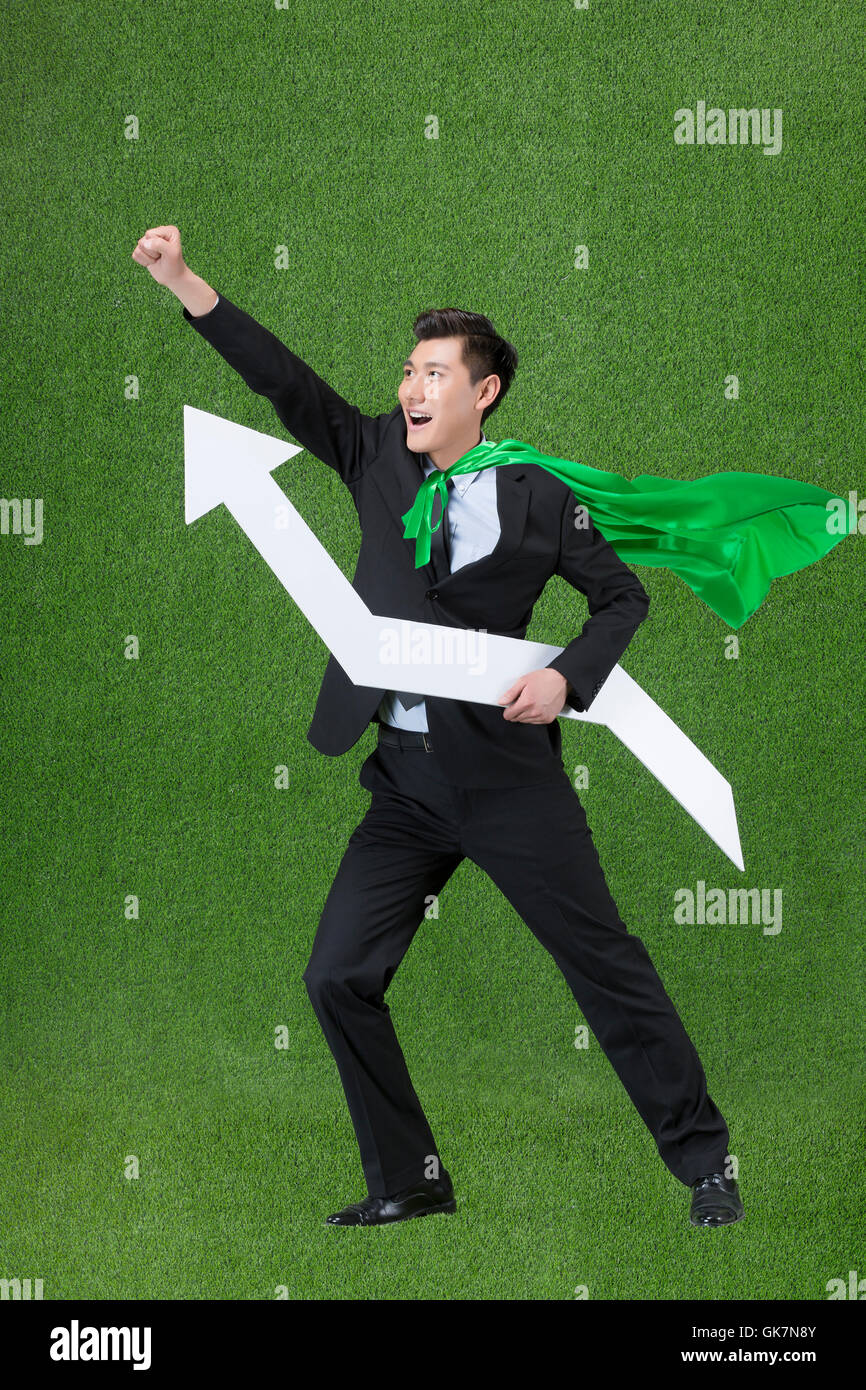 Creative business man dressed in grass green cloak holding arrow sign ...