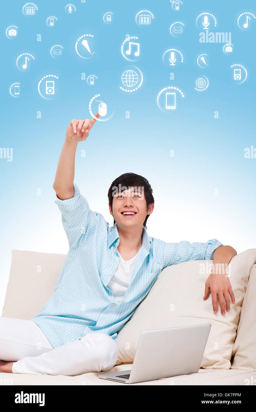 Young man sitting on the couch using a computer Stock Photo - Alamy
