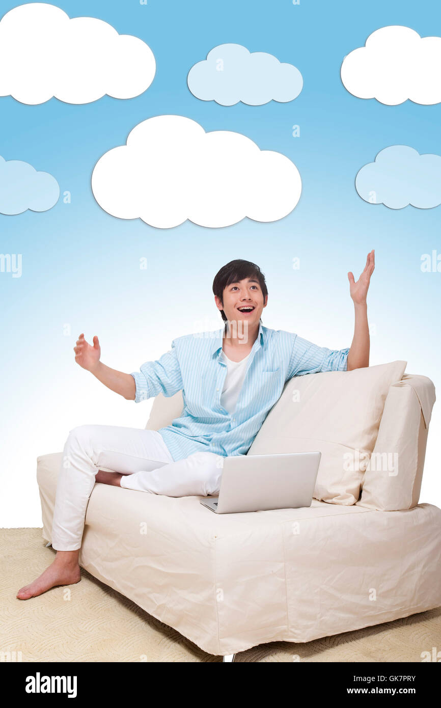 Young man sitting on the couch using a computer Stock Photo - Alamy