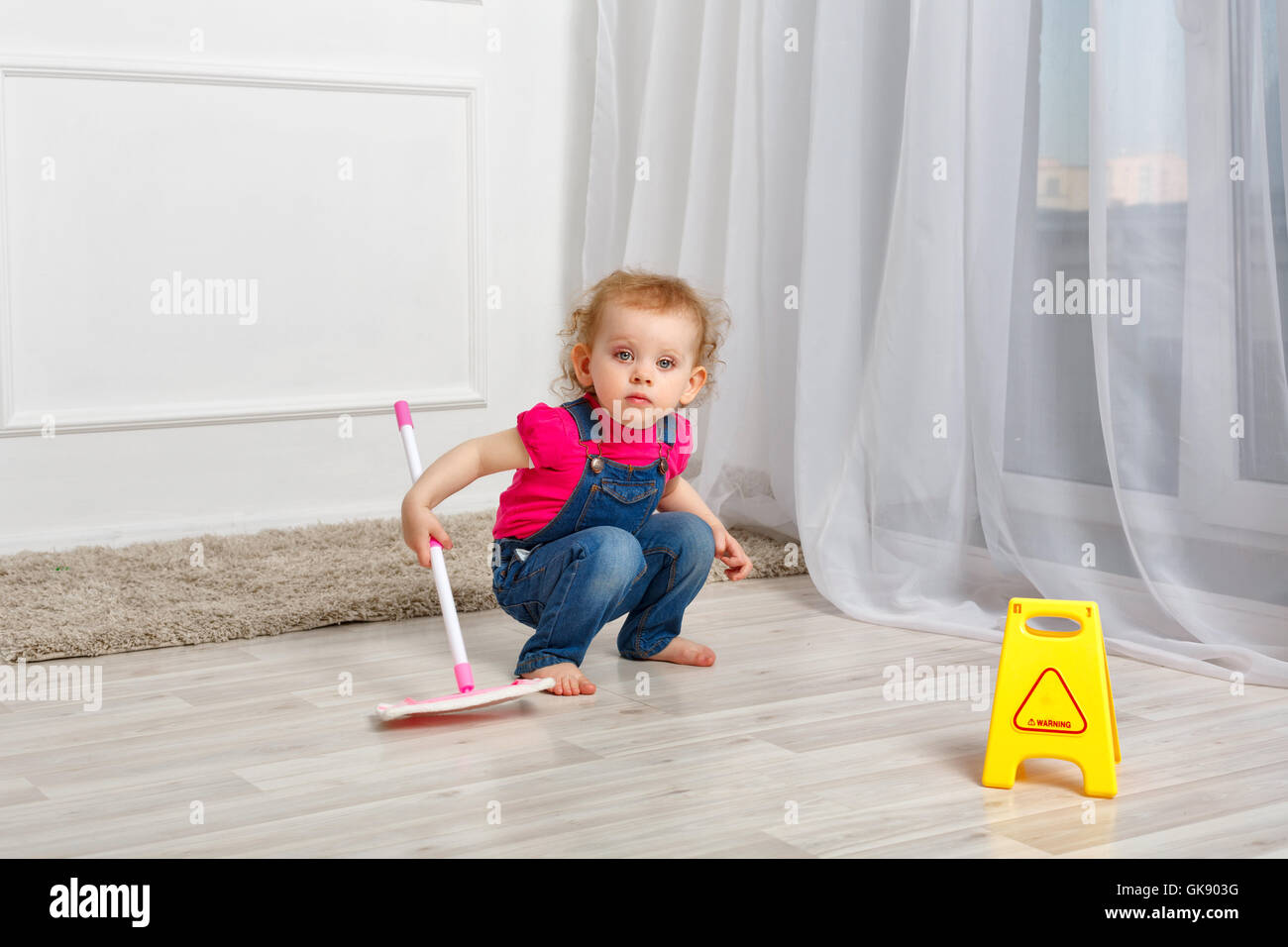 Little girl holding a mop in her hands. Little helper. Household chores ...