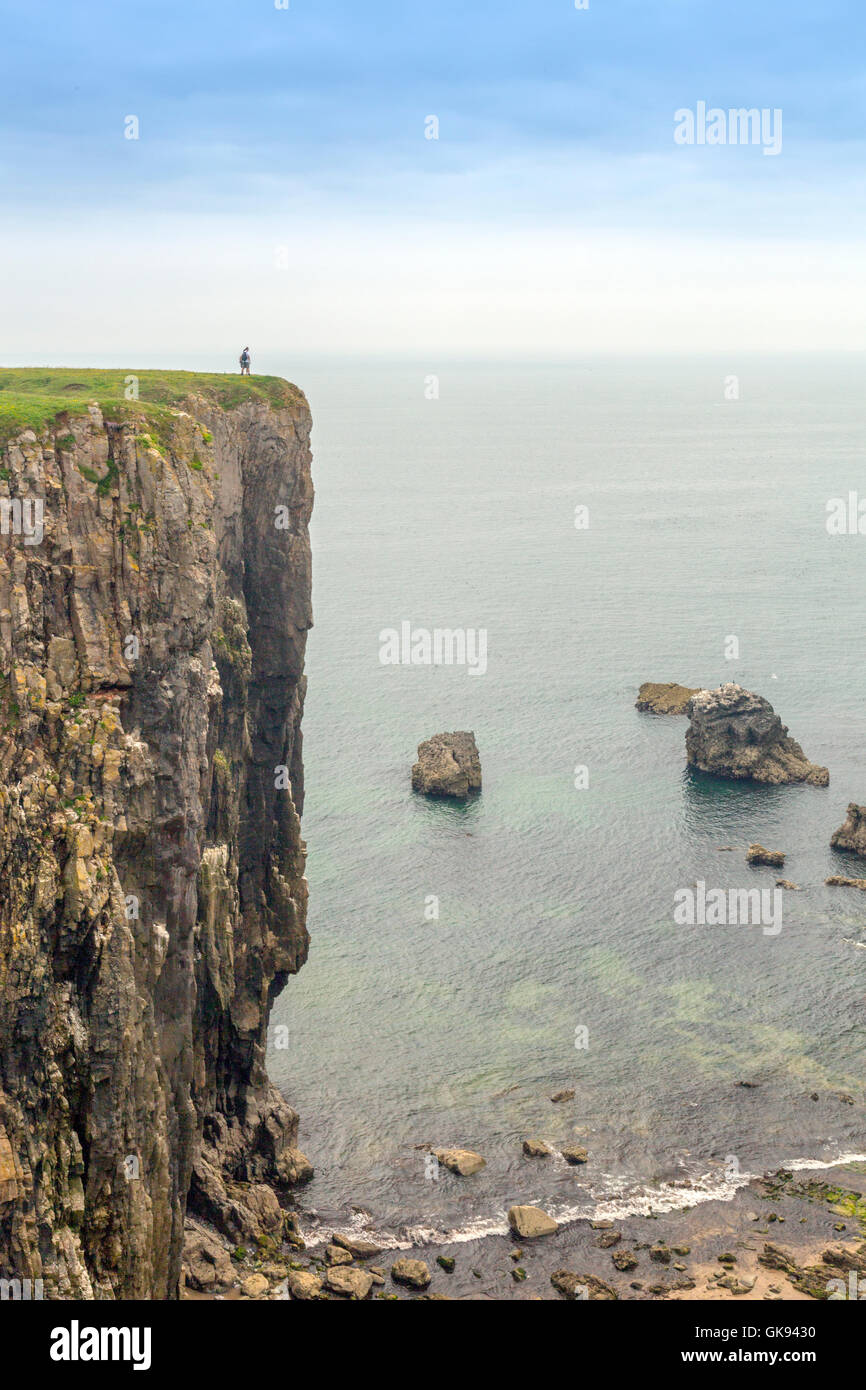 Two walkers close to the edge of the vertical cliffs near Elegug Stacks ...