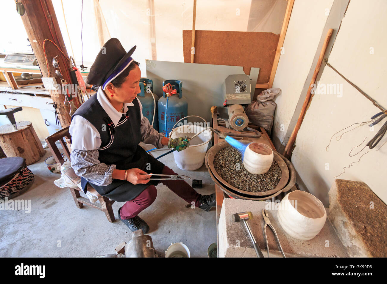Heqing, China - March 16, 2016: Bayi woman making a silver pot. Heqing ...