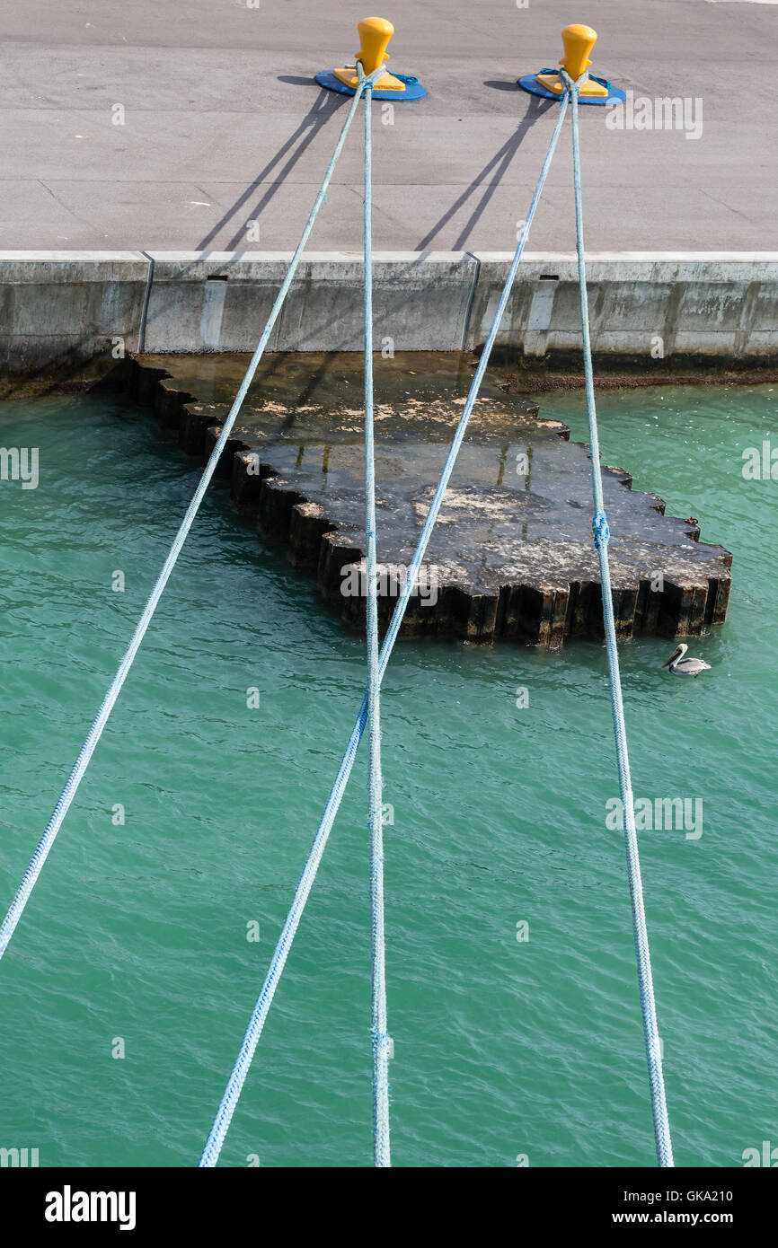 Blue ropes to yellow bollards on a concrete pier Stock Photo - Alamy