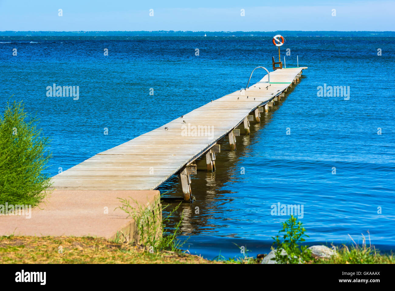 Long and narrow wooden bathing pier stretching out into the sea. A red ...