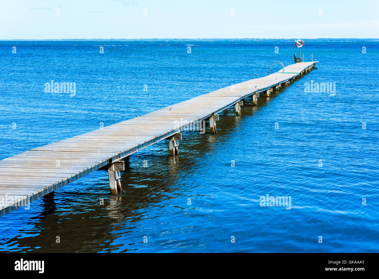 Long and narrow wooden bathing pier stretching out into the sea. A red ...