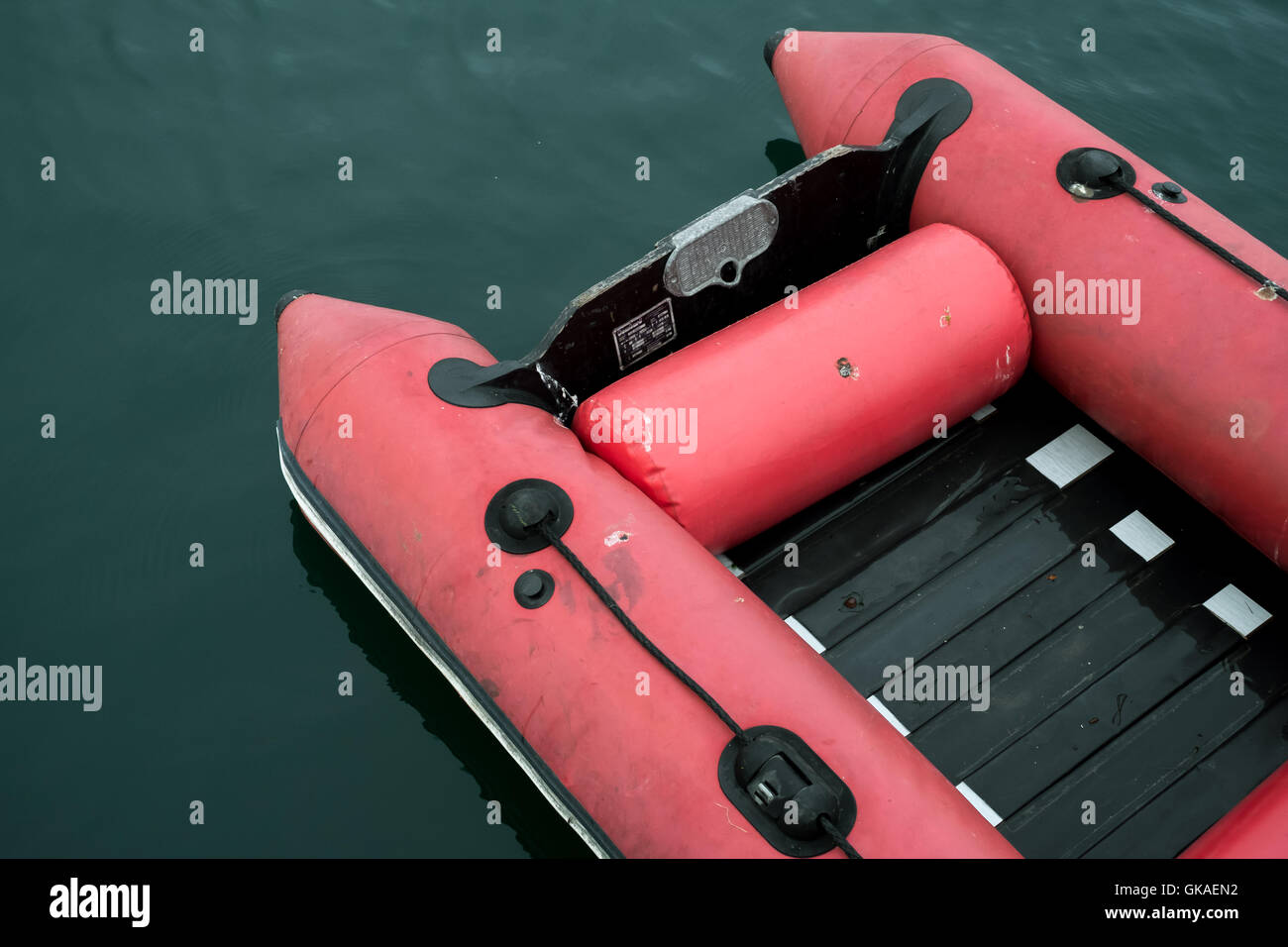 A red rigid inflatable dinghy contrasted against the green waters of ...