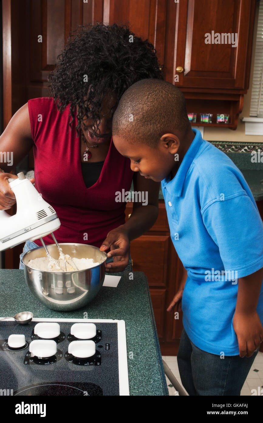 African American mother and son making cookies in kitchen and in ...