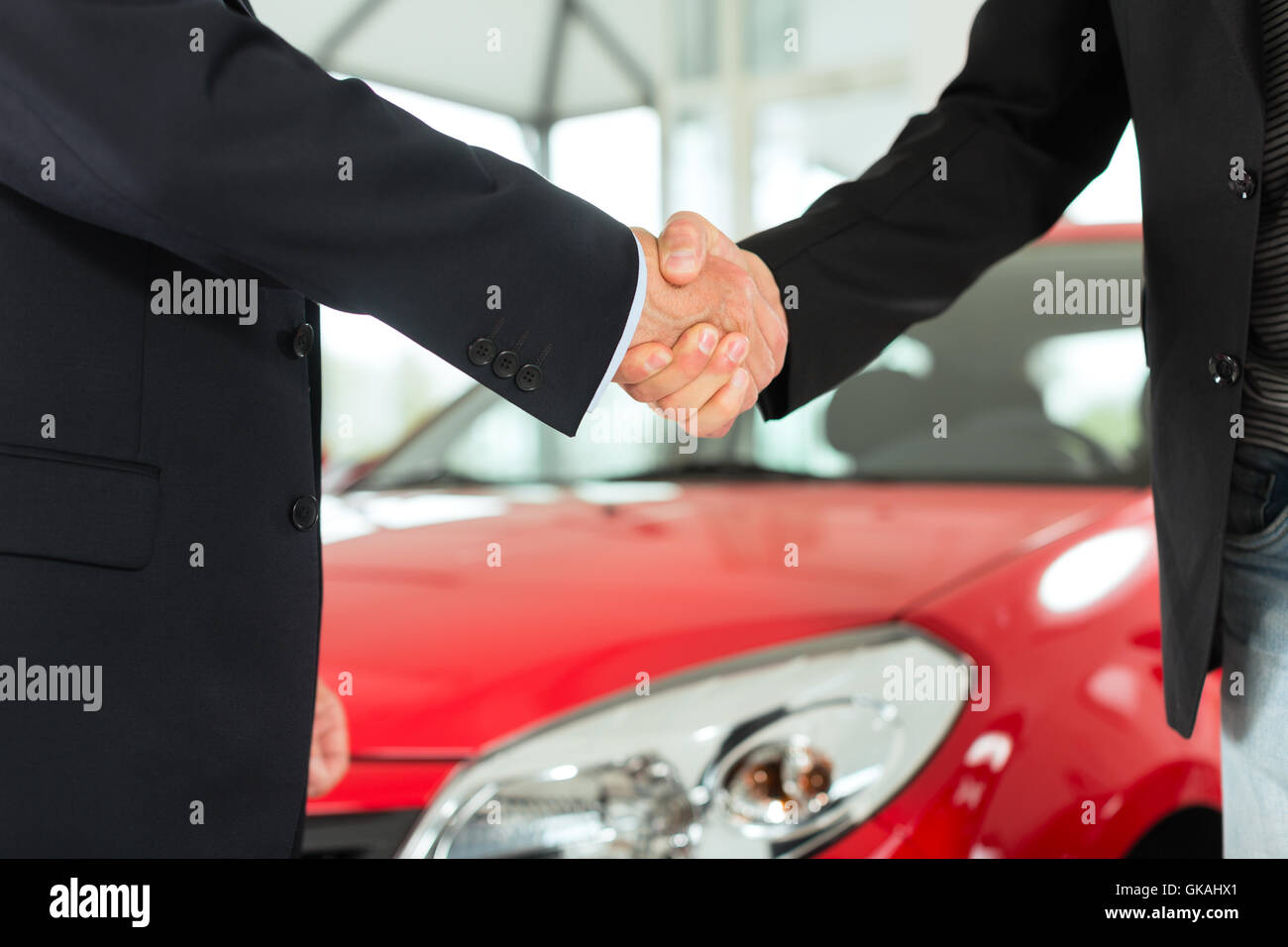 handshake between two men in suits against red car Stock Photo - Alamy