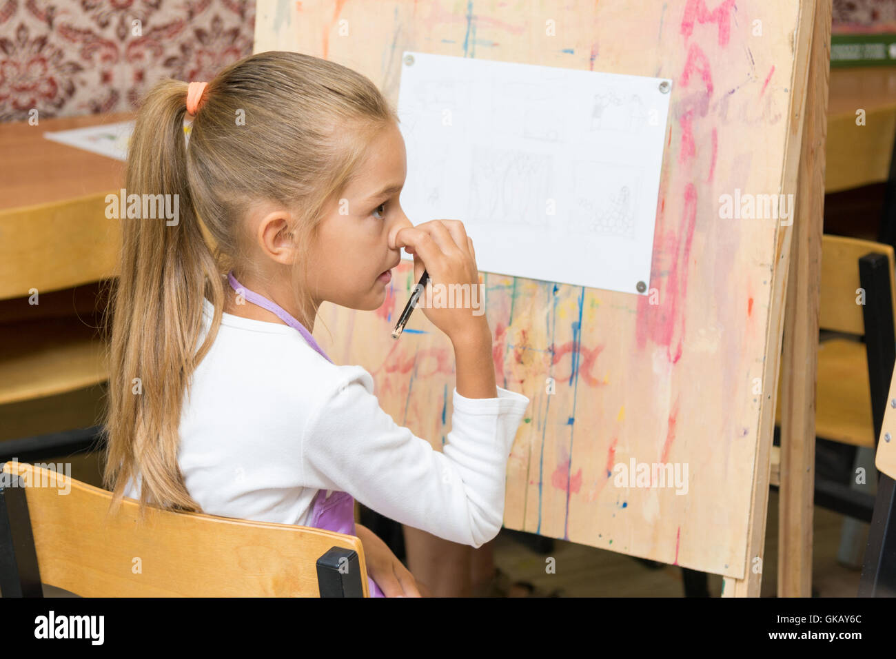 Girl scratching nose listening to the teacher carefully at drawing ...